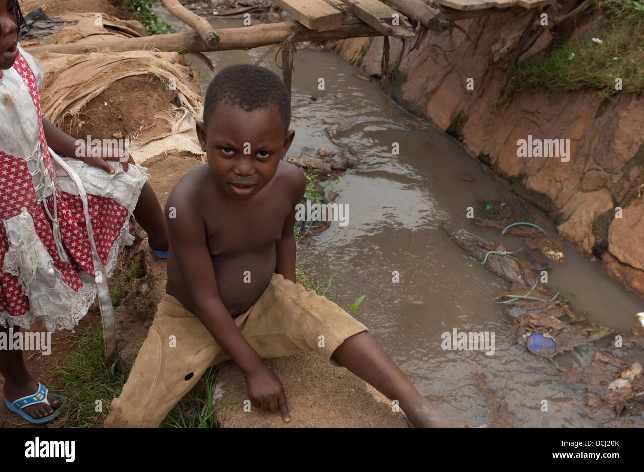 child sitting by drainage ditch in african slum Stock Photo - Alamy