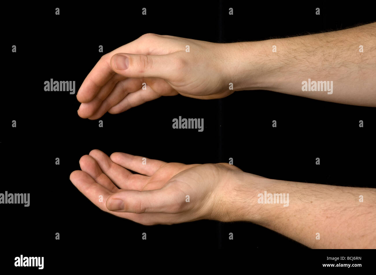 male hands enclosing and encompassing and cupping against black Stock ...