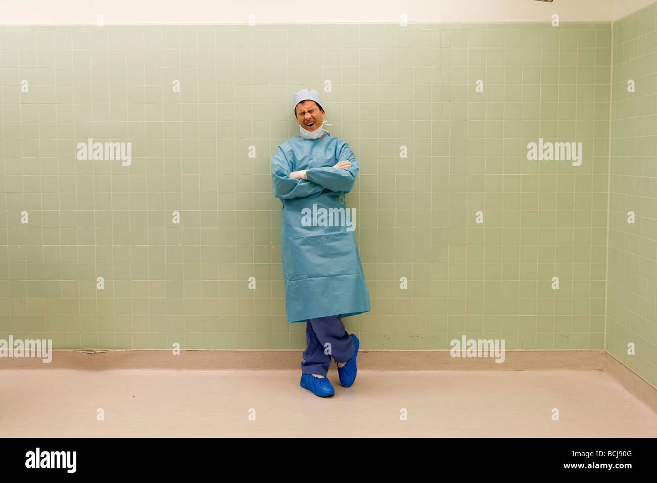 Caucasian male surgeon/doctor in blue surgical scrubs leaning against ...