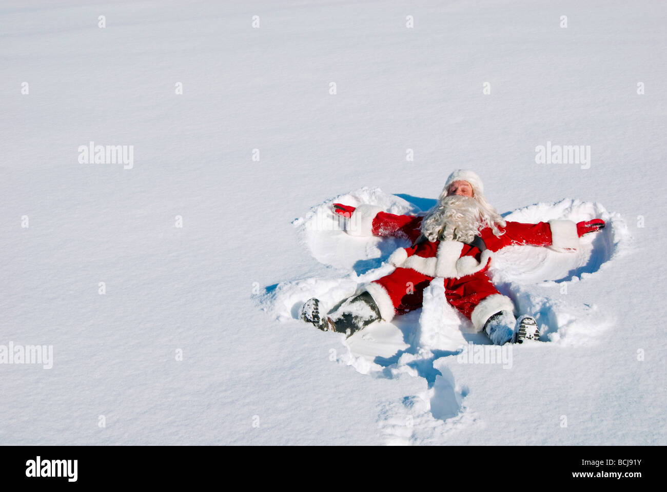 Santa making a snow angel in fresh snow Stock Photo - Alamy