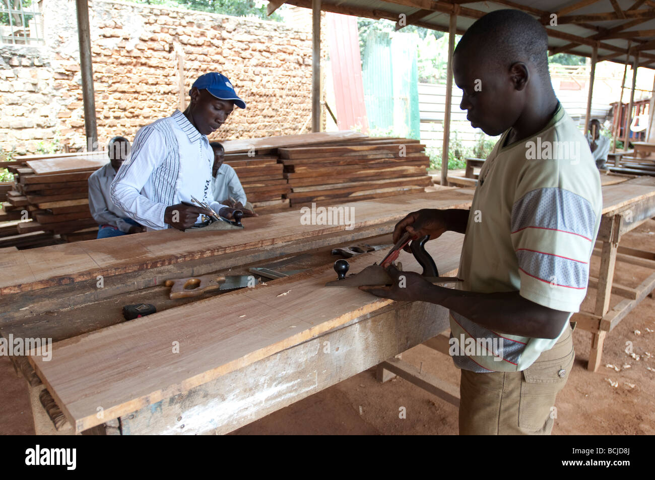 Carpenters planing wood in african workshop Stock Photo - Alamy