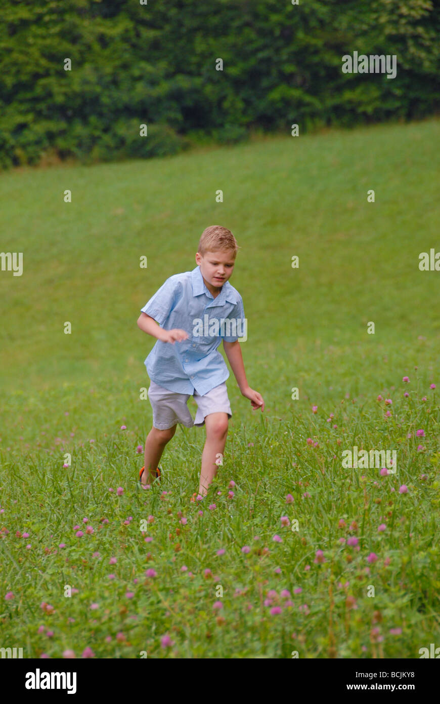 Young boy running in a grassy field on a summer day Stock Photo - Alamy