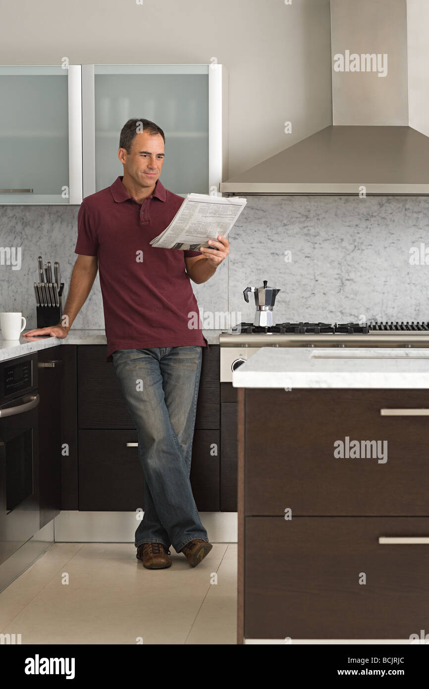 Man reading a newspaper in kitchen Stock Photo - Alamy