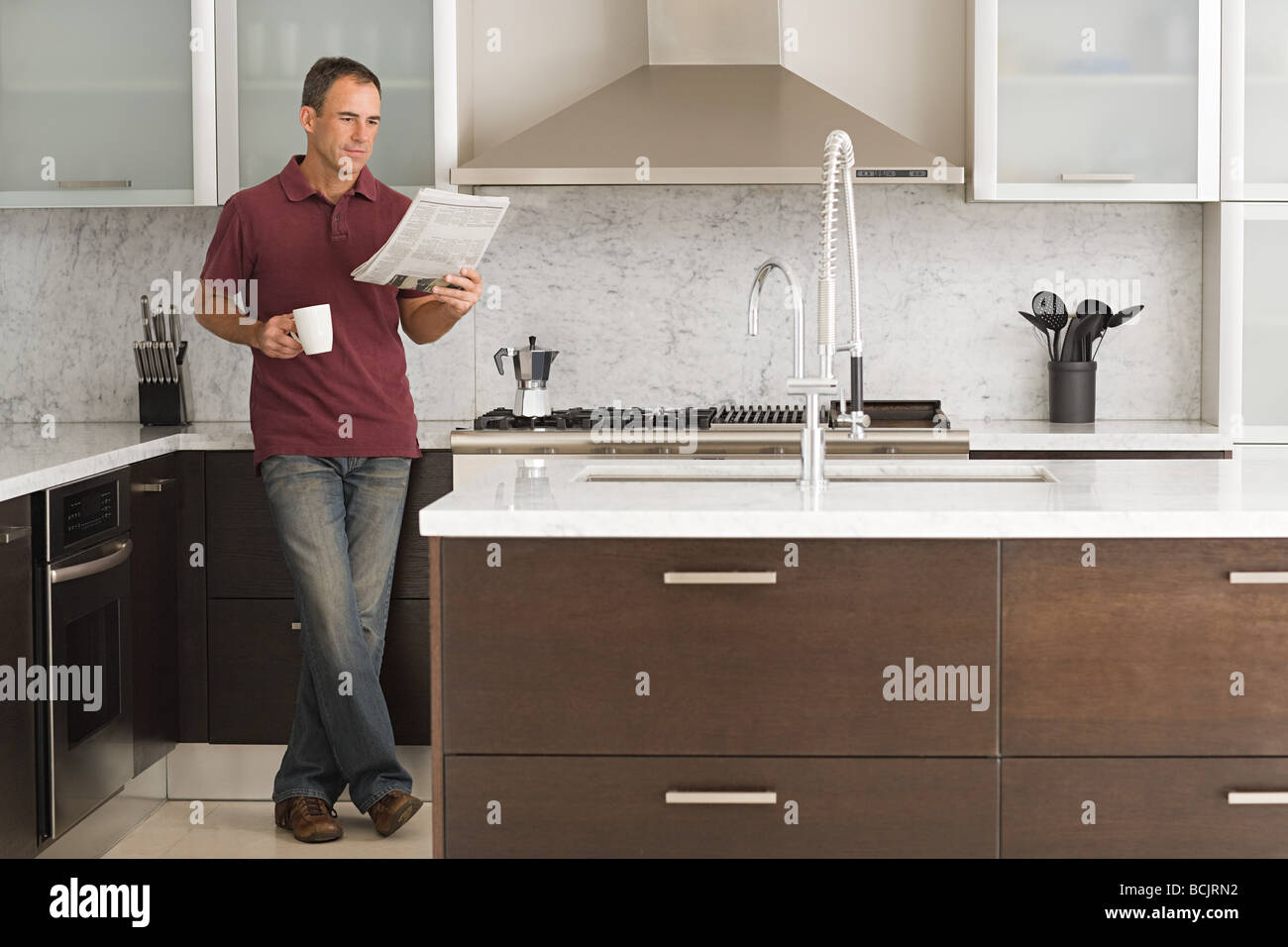 Man reading a newspaper in kitchen Stock Photo - Alamy