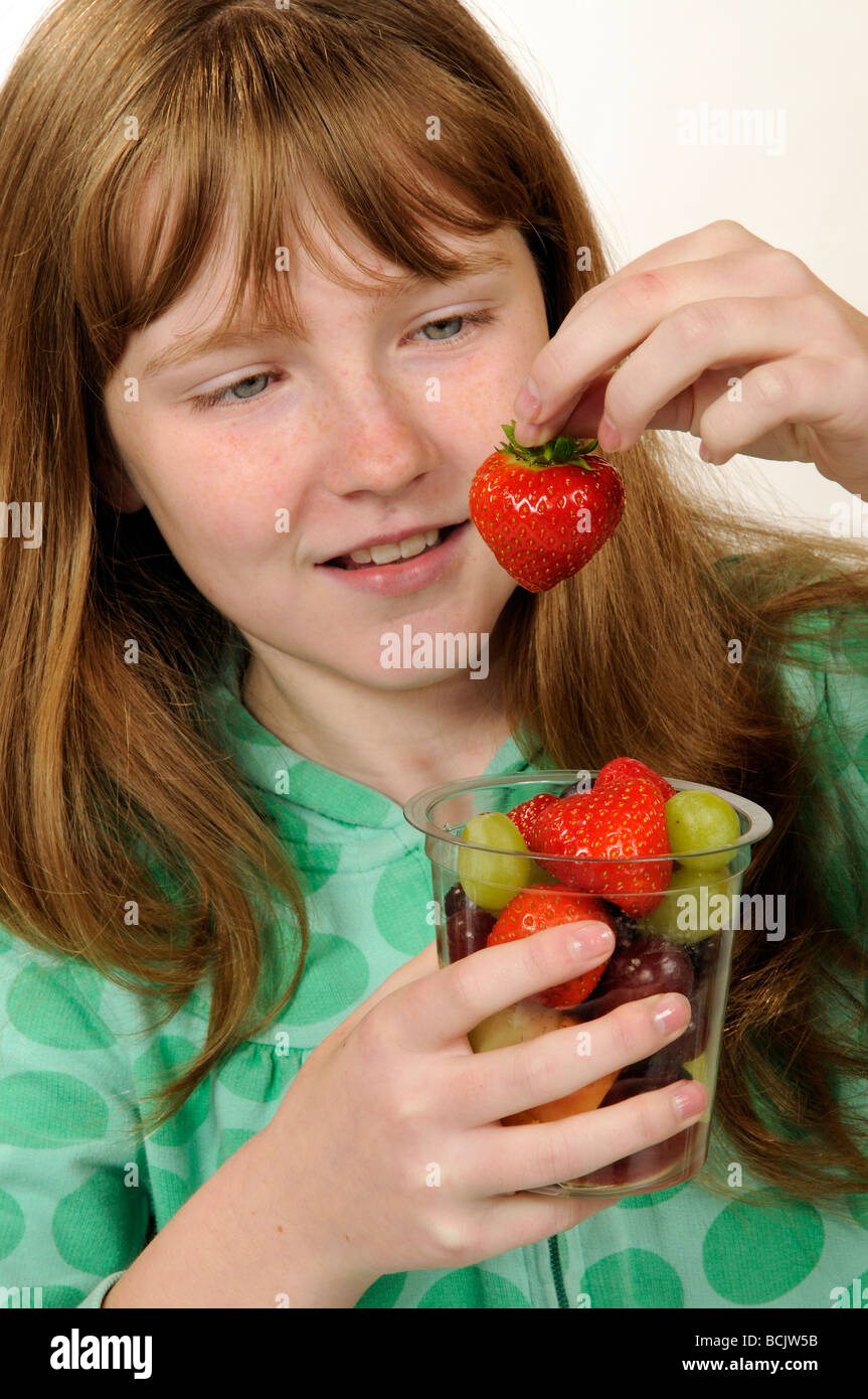 Girl eating a fresh fruit salad and holding a strawberry Stock Photo ...