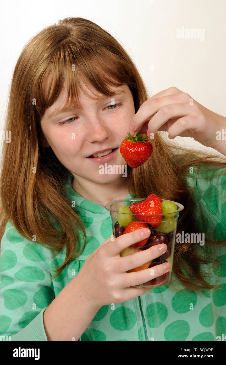 Girl eating a fresh fruit salad and holding a strawberry Stock Photo ...
