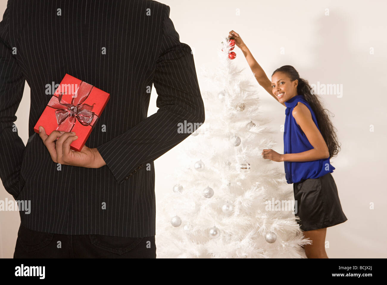 Man hiding a christmas gift behind back Stock Photo - Alamy