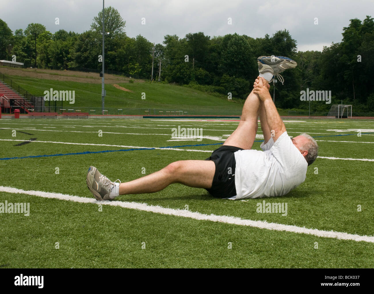 overweight middle age retired and active senior man stretching his leg ...