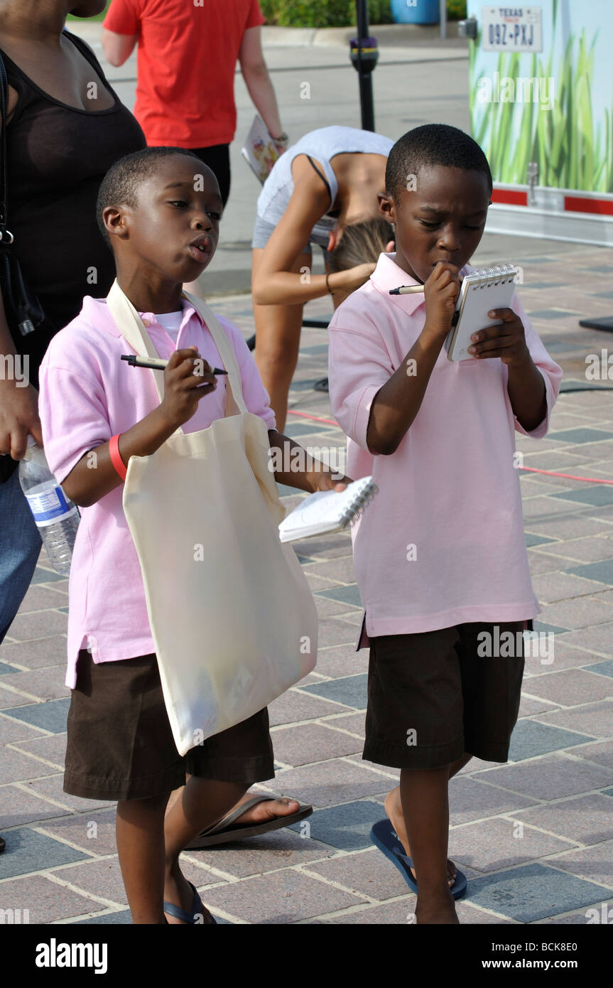 Twin boys writing in notebooks as they walk Stock Photo - Alamy