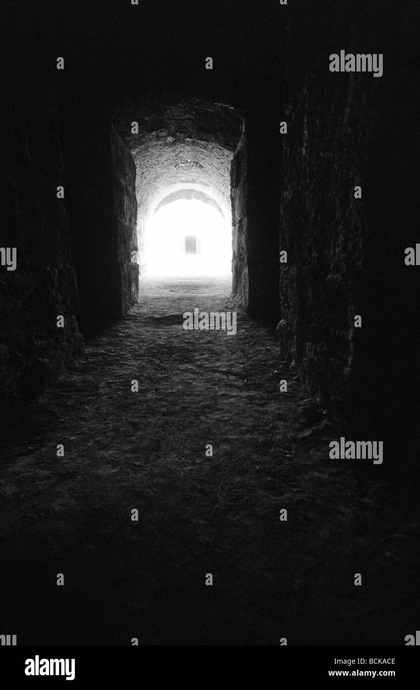 Dark passageway with lit arch at end, b&w Stock Photo - Alamy