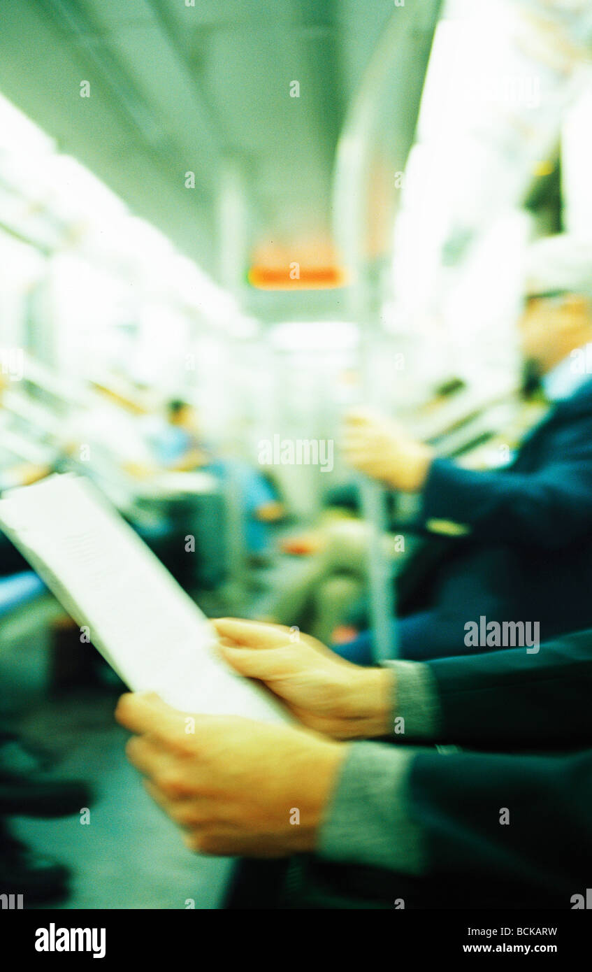 Man holding paper in hands on subway, blurred Stock Photo - Alamy