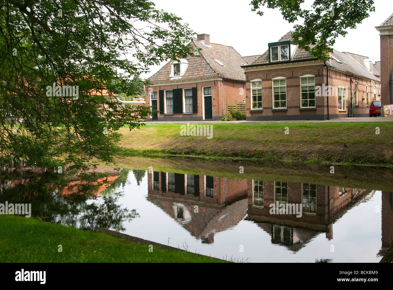 Typical Dutch red brick buildings casting a reflection in the still ...