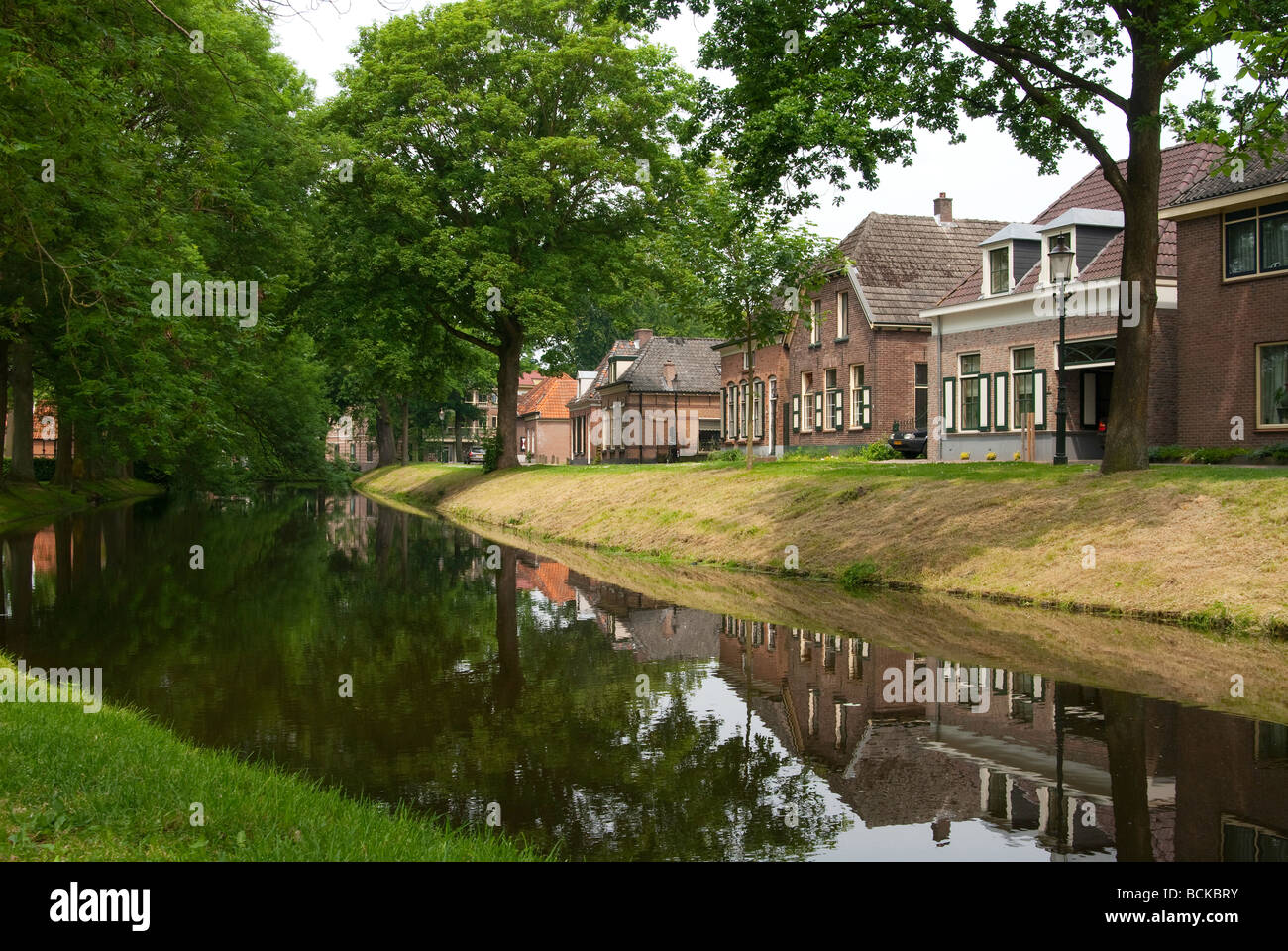 Typical Dutch red brick buildings casting a reflection in the still ...