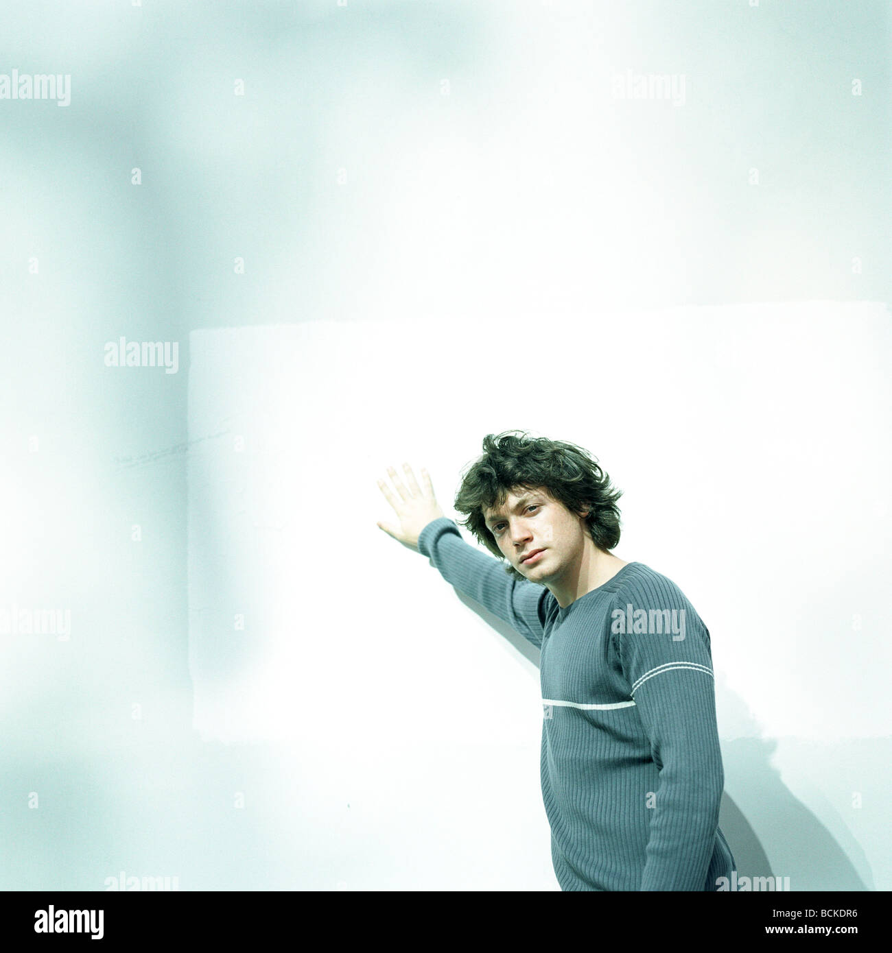 Young man leaning hand against wall Stock Photo - Alamy