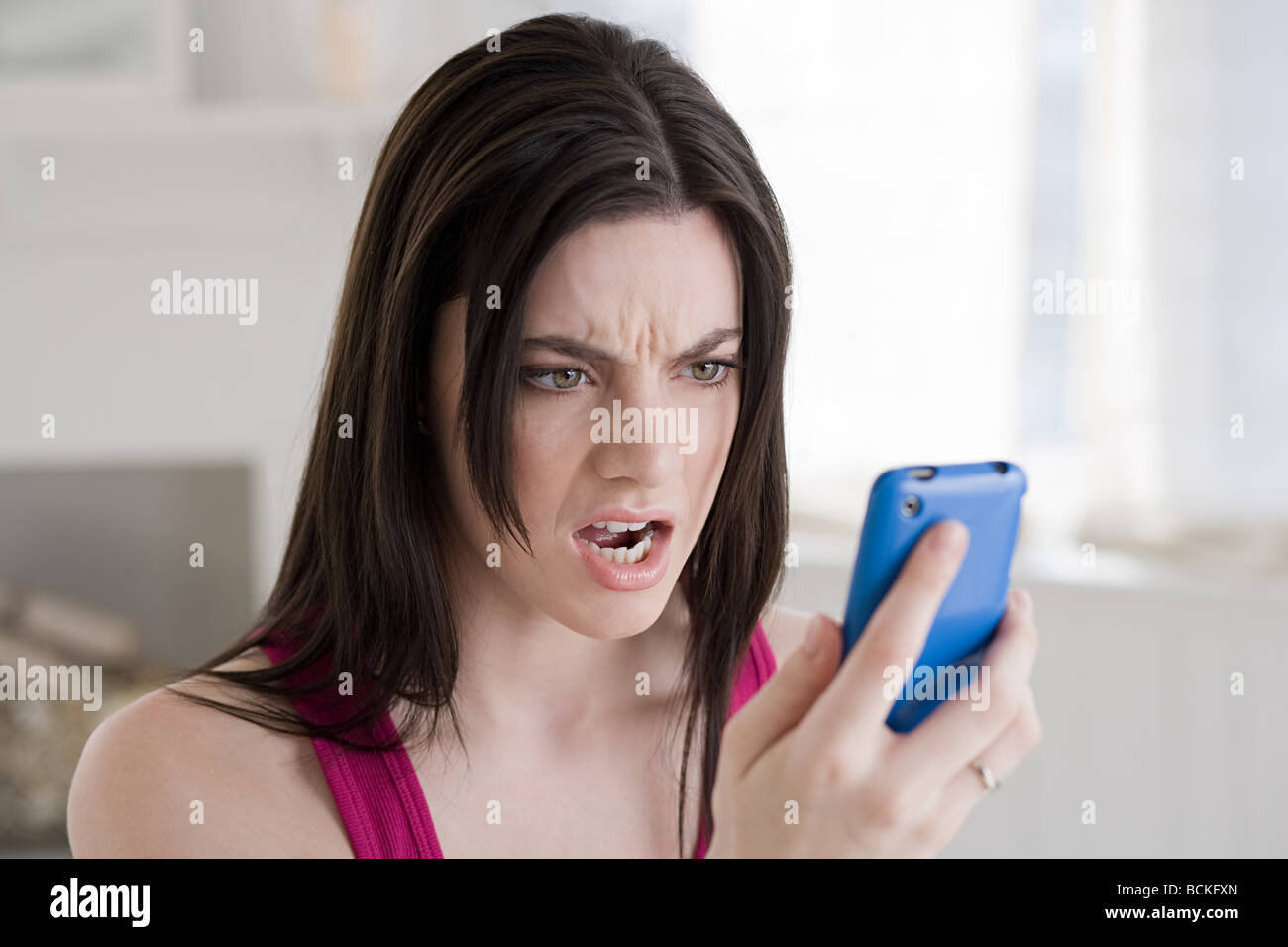 Angry woman looking at cellphone Stock Photo - Alamy