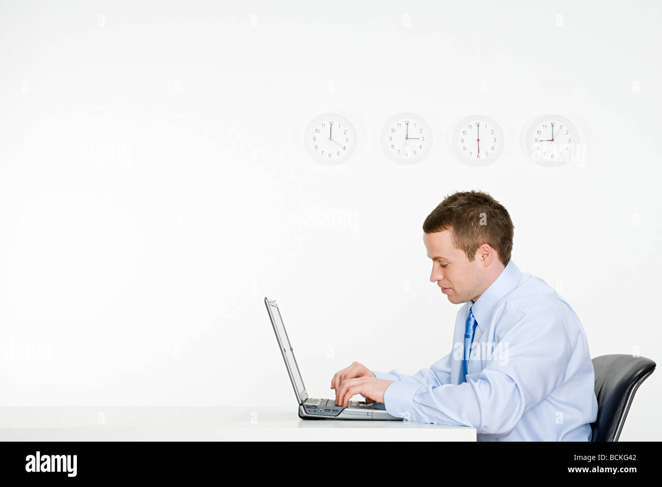 Office worker with laptop and wall clocks Stock Photo - Alamy
