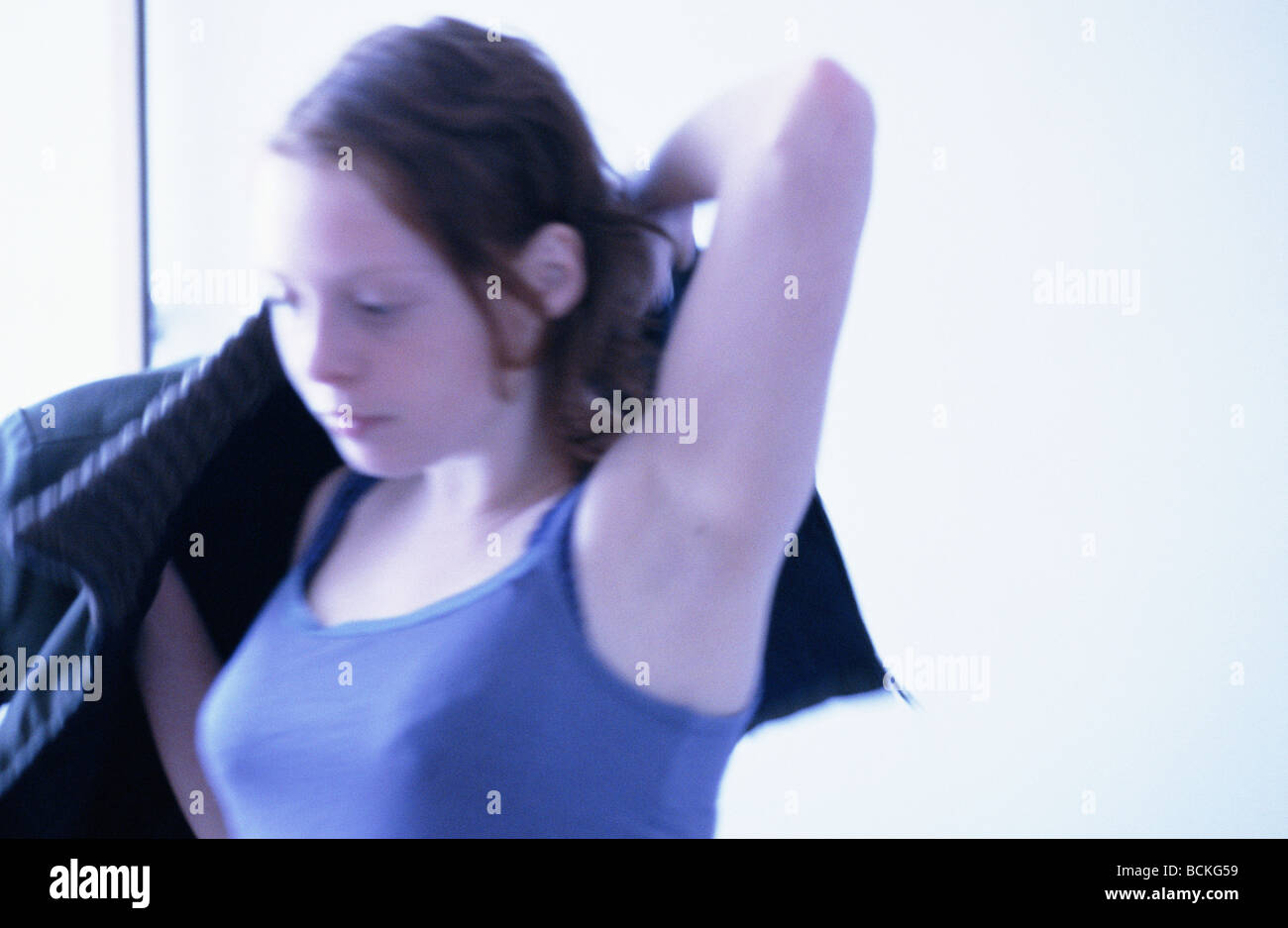 Young woman putting on jacket Stock Photo - Alamy