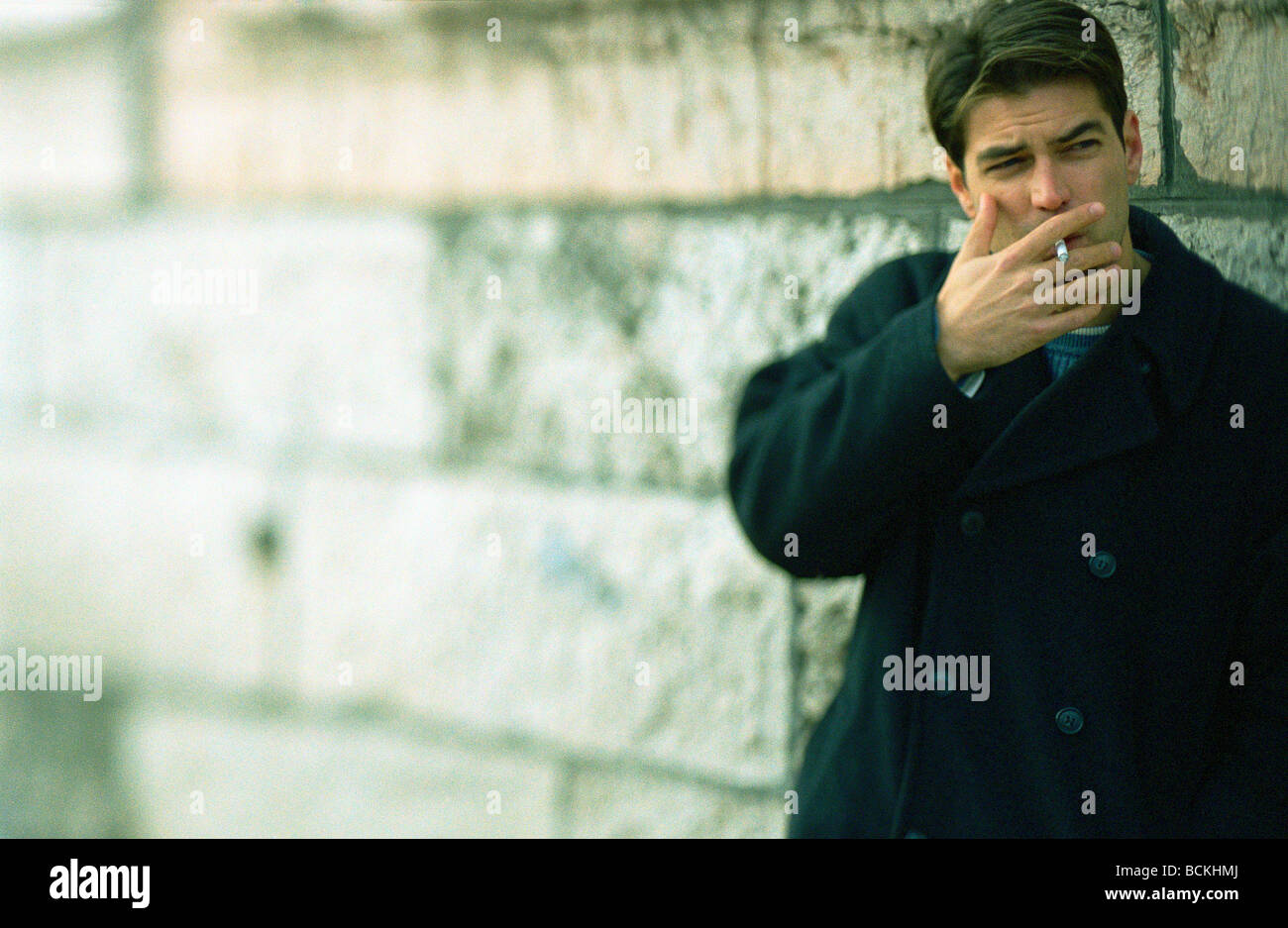 Man leaning against wall smoking cigarette hi-res stock photography and ...
