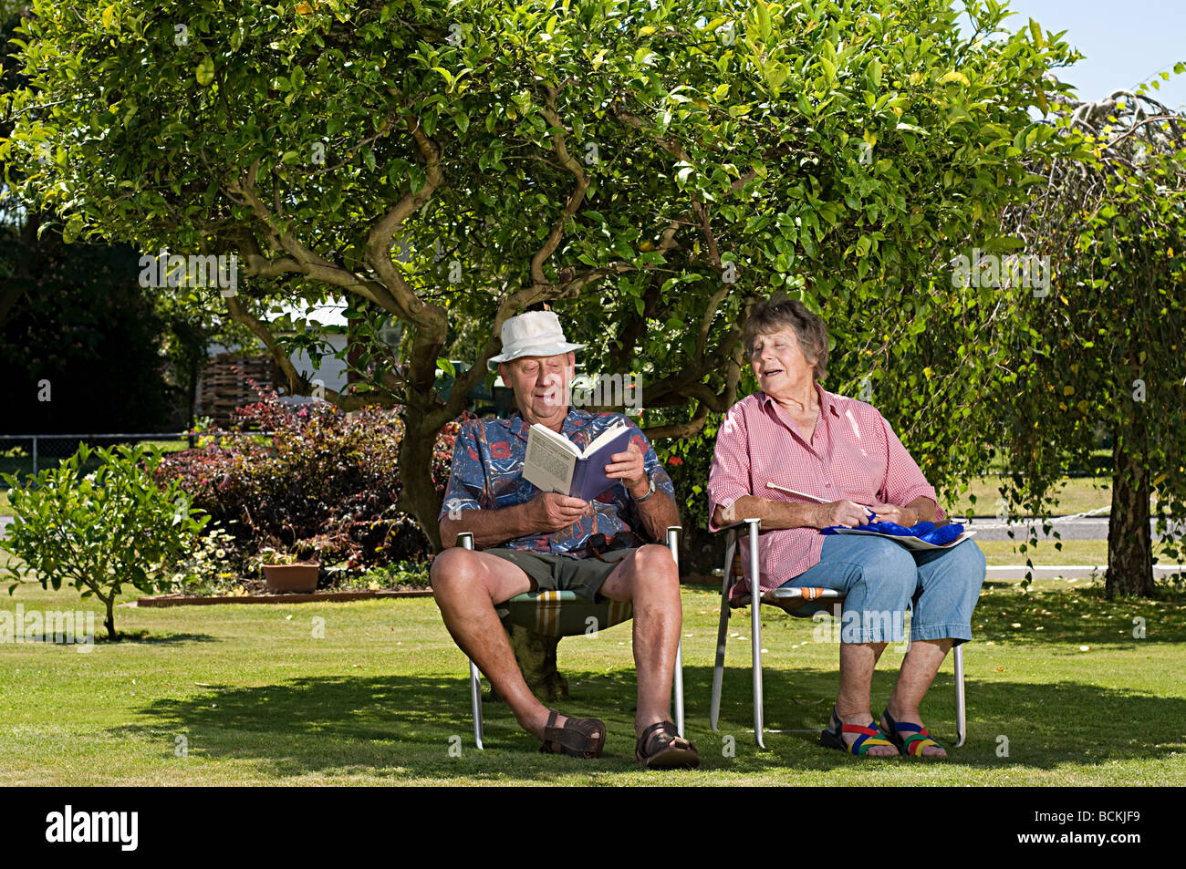 Senior couple relaxing under a tree in the garden Stock Photo - Alamy