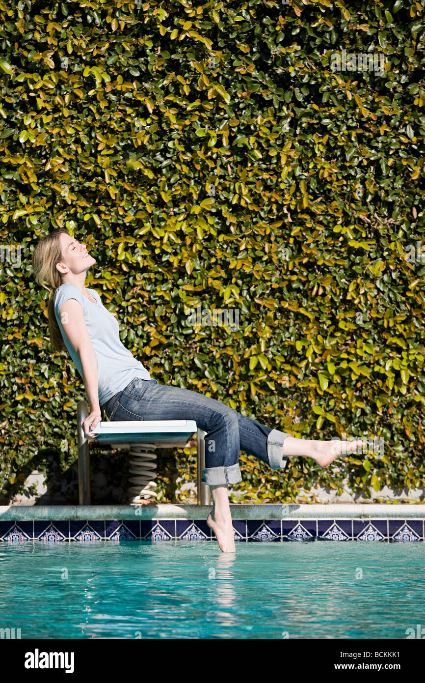 Woman sitting by pool Stock Photo - Alamy
