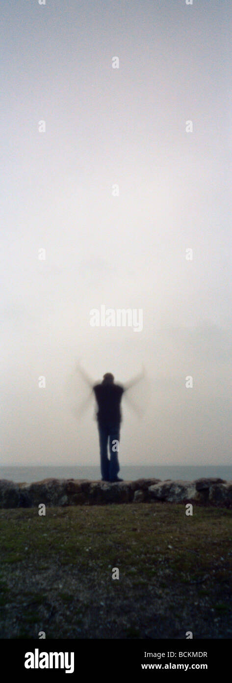 Person silhouetted in front of seascape, flapping arms, vertical Stock ...