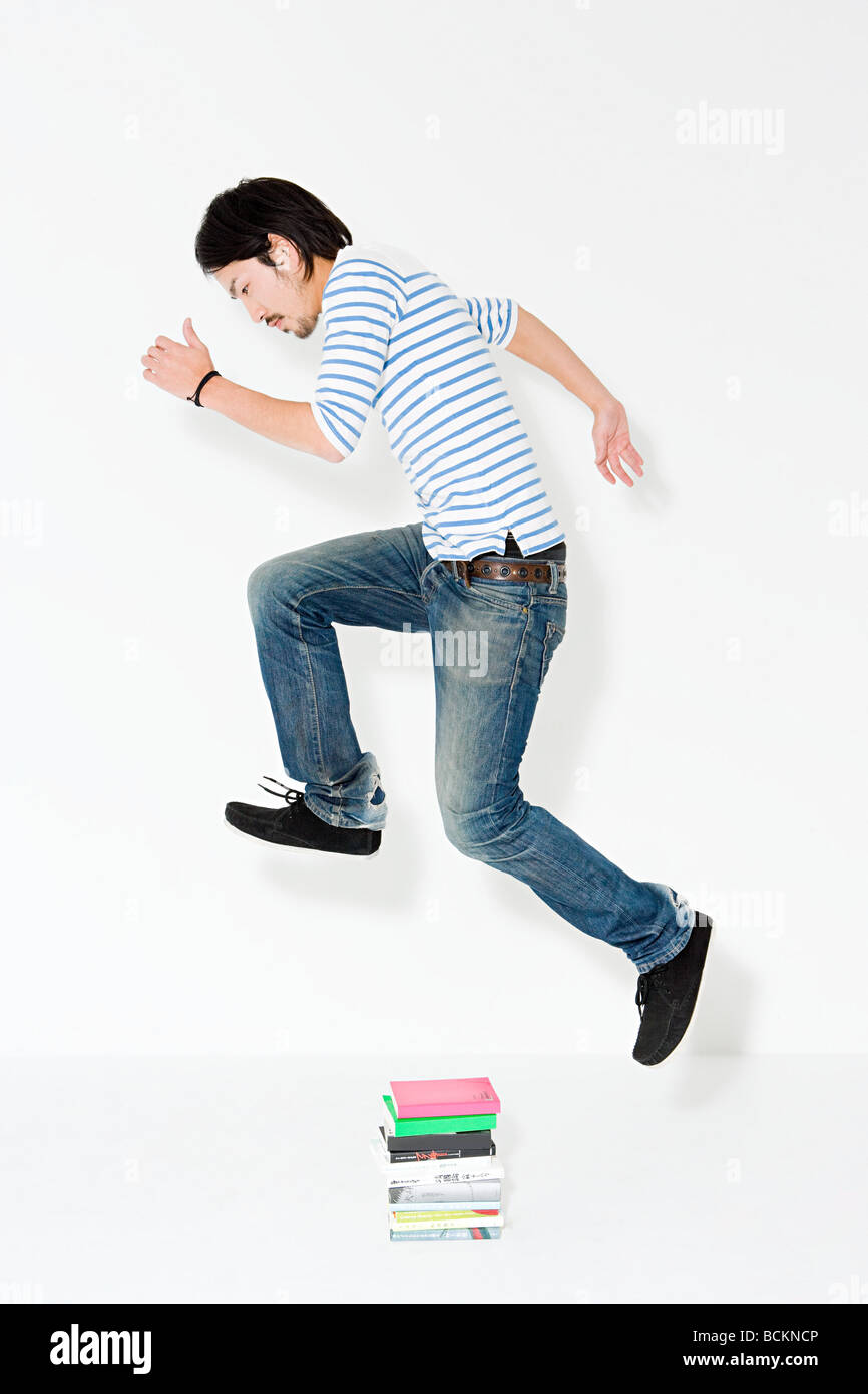 Young man jumping over books Stock Photo - Alamy