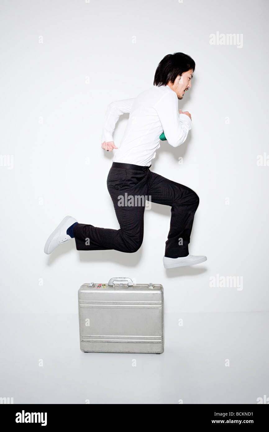 Man jumping over briefcase Stock Photo - Alamy