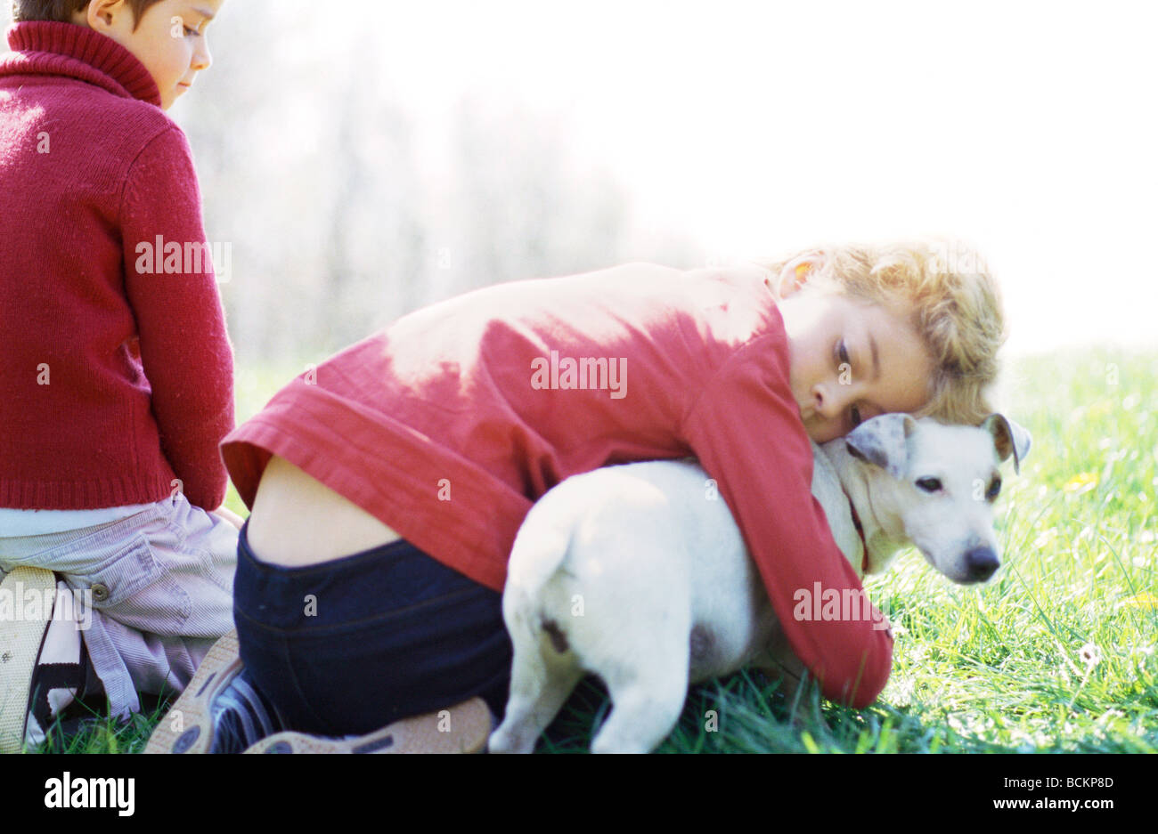 Children sitting on grass, one hugging dog Stock Photo - Alamy