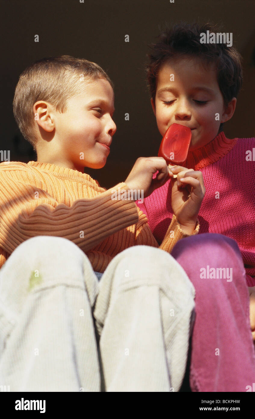 Boy sharing popsicle with girl, low angle view Stock Photo - Alamy