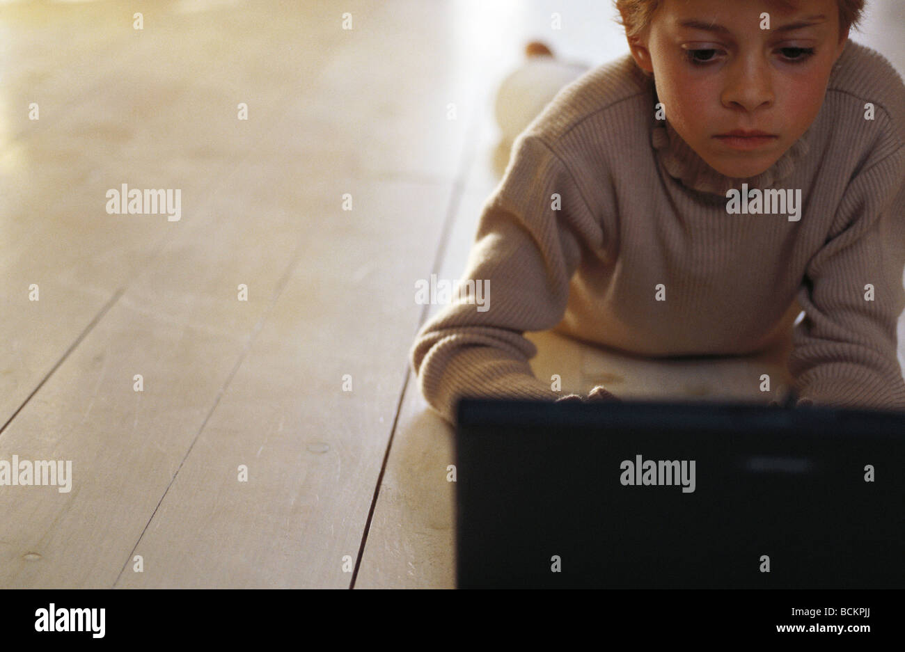 Child lying on floor looking at laptop computer Stock Photo - Alamy