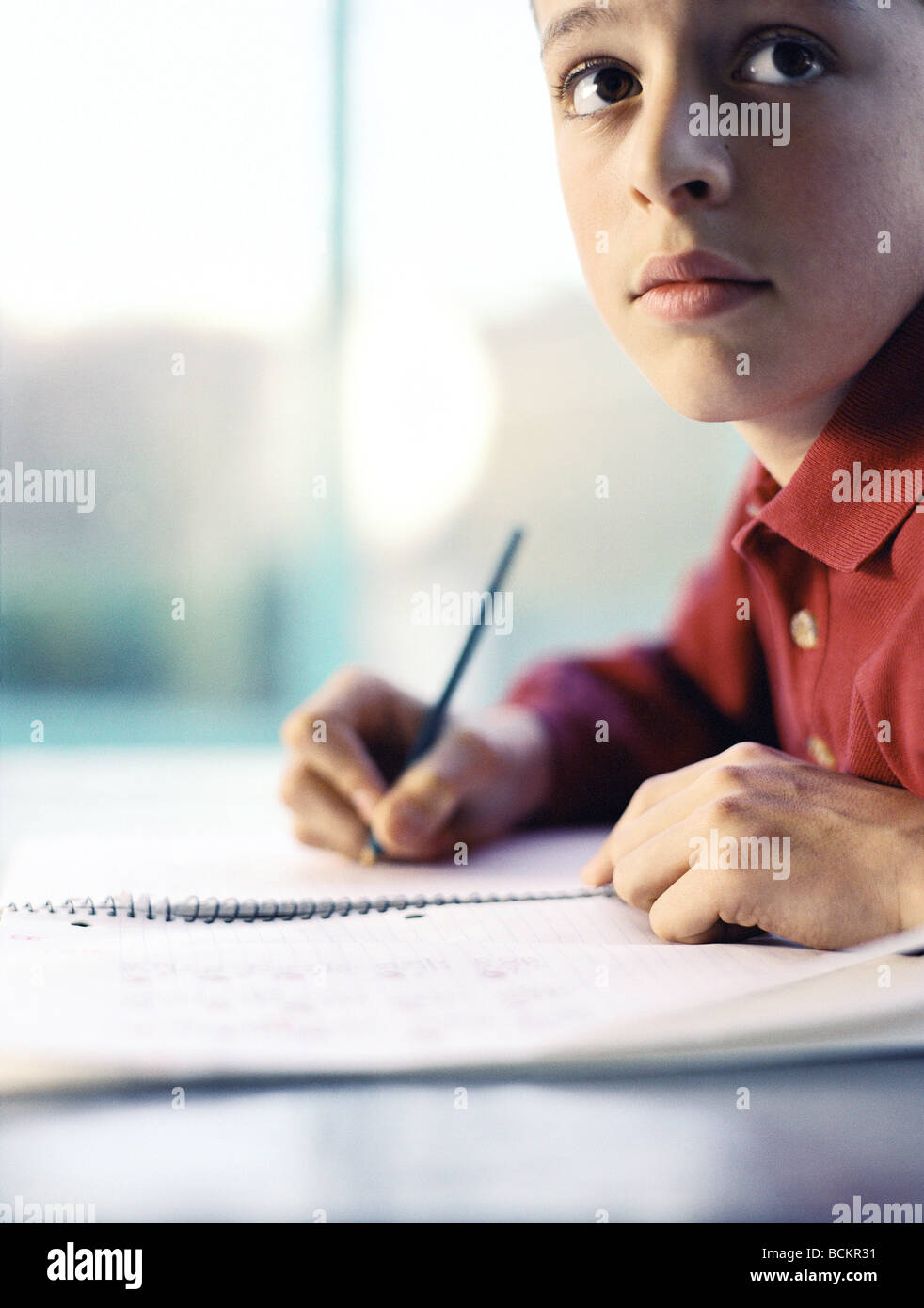 Boy writing at table Stock Photo - Alamy