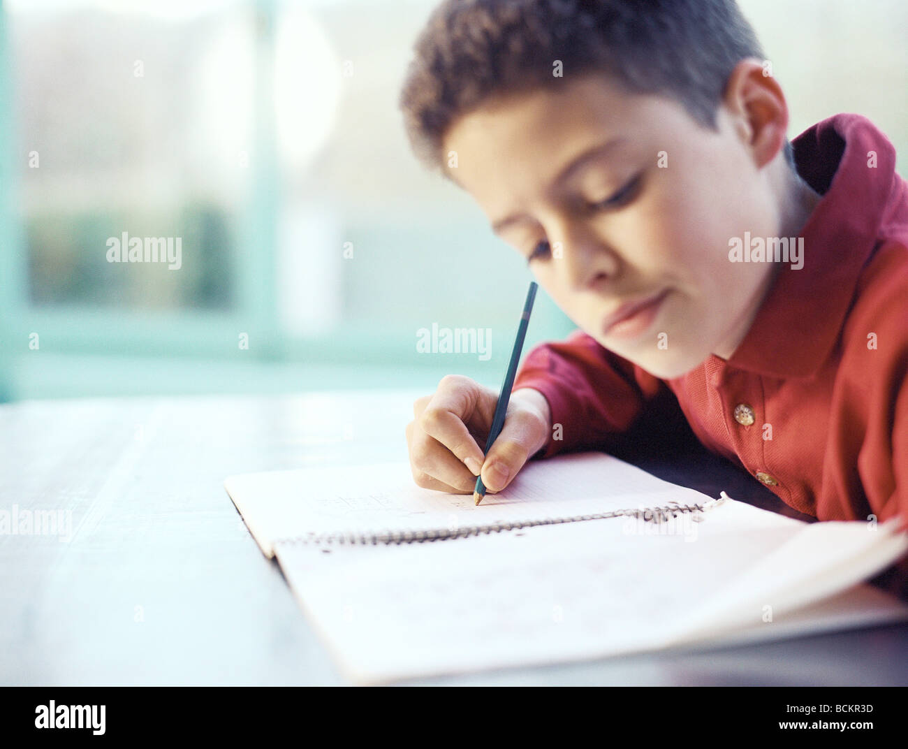 Boy writing at table Stock Photo - Alamy