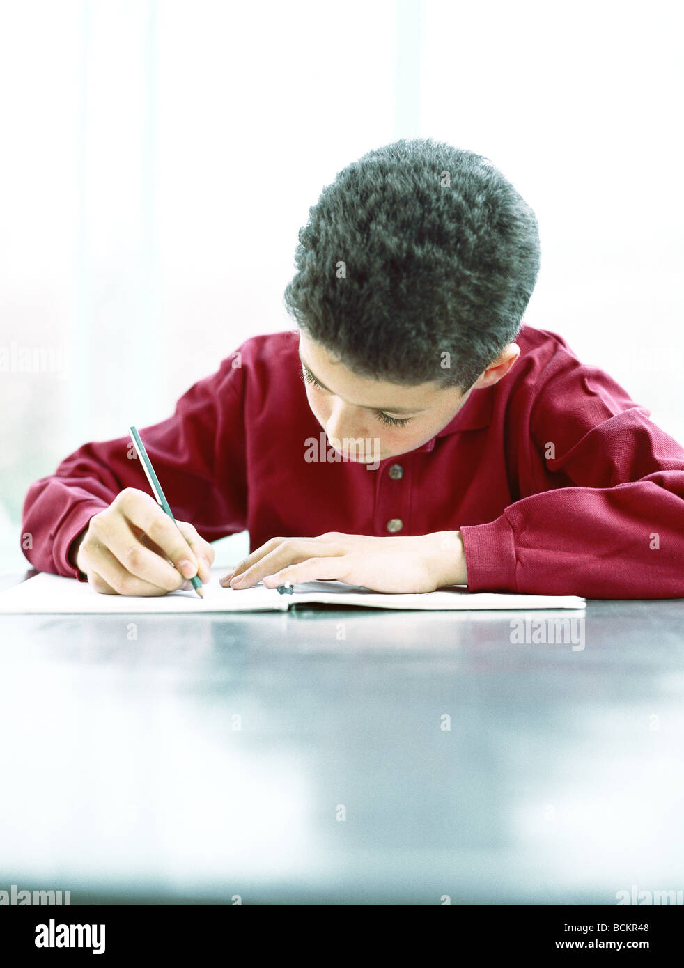 Boy writing at table, front view Stock Photo - Alamy