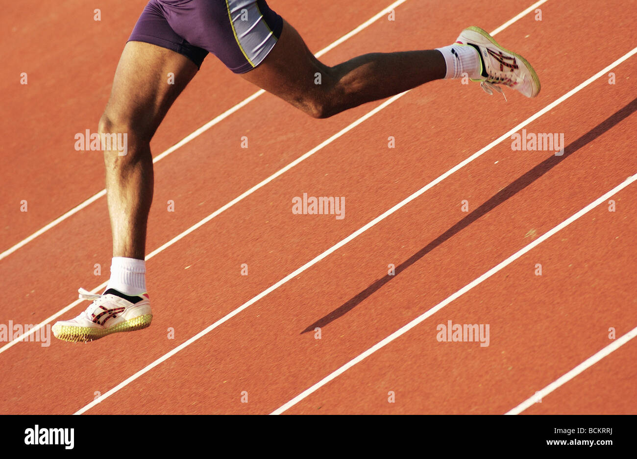 Runner running on clay track, lower section Stock Photo - Alamy