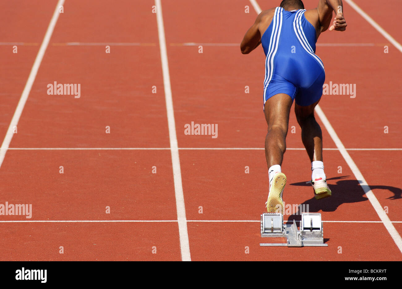 Runner leaving starting block, rear view Stock Photo - Alamy