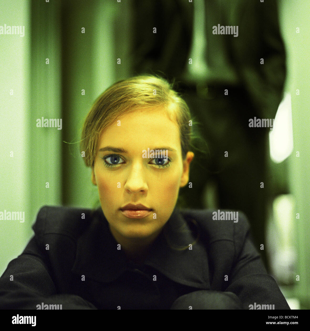 Woman looking at camera, man standing in background Stock Photo - Alamy