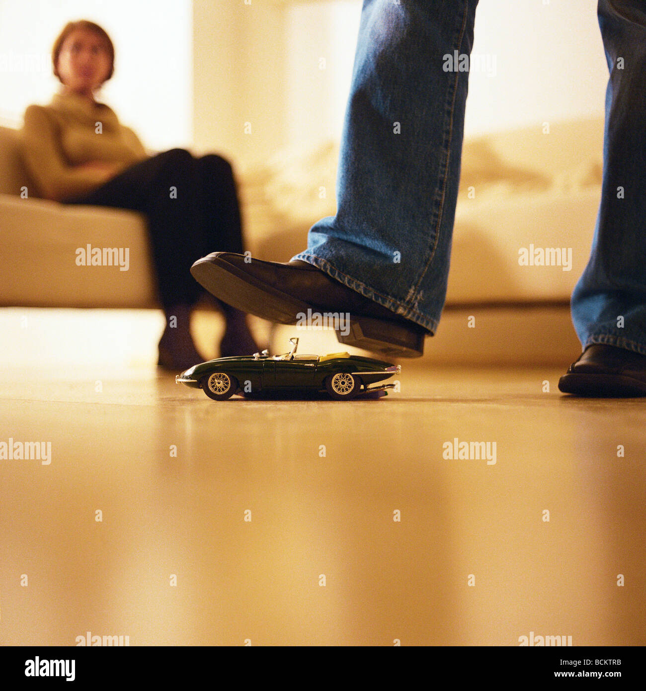 Man's foot over toy car, woman sitting in background Stock Photo - Alamy
