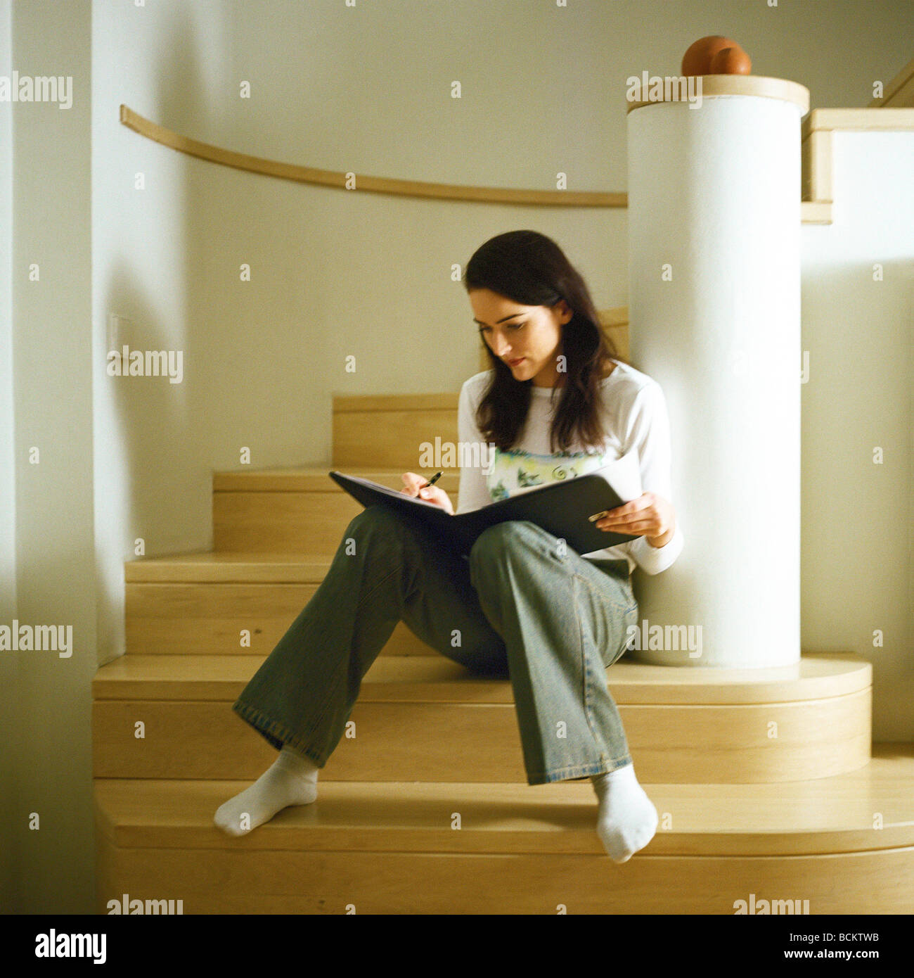 Woman sitting on steps with file, writing Stock Photo - Alamy