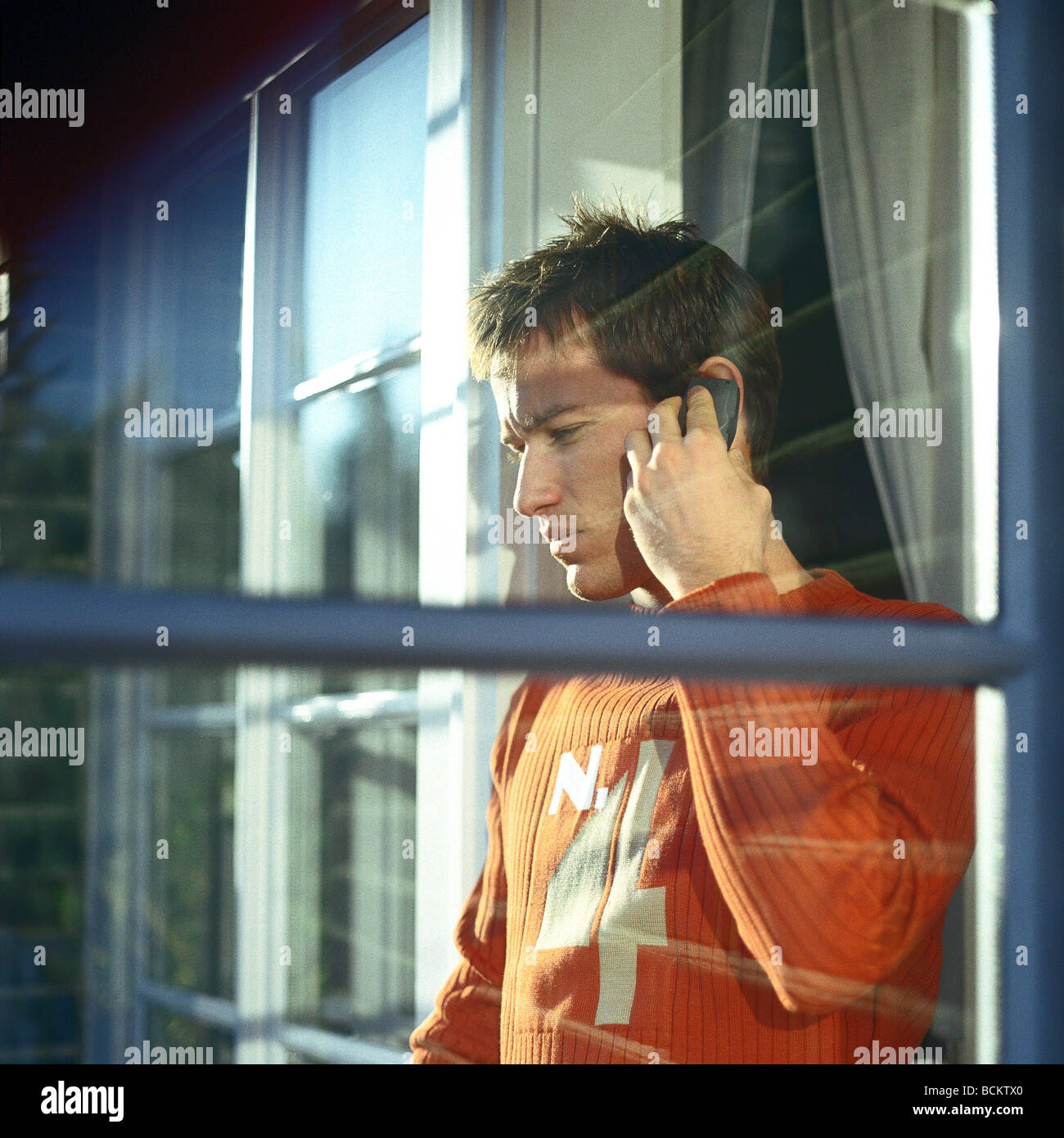 Man using cell phone, seen through window Stock Photo - Alamy