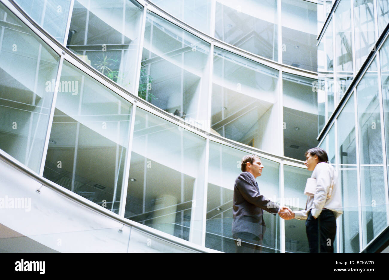 Two businessmen meeting in office lobby, low angle view Stock Photo - Alamy