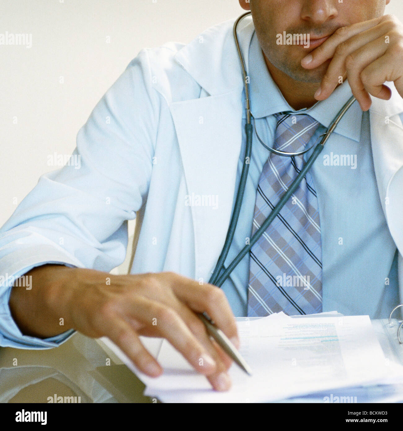 Doctor wearing stethoscope and holding pen, partial view Stock Photo ...