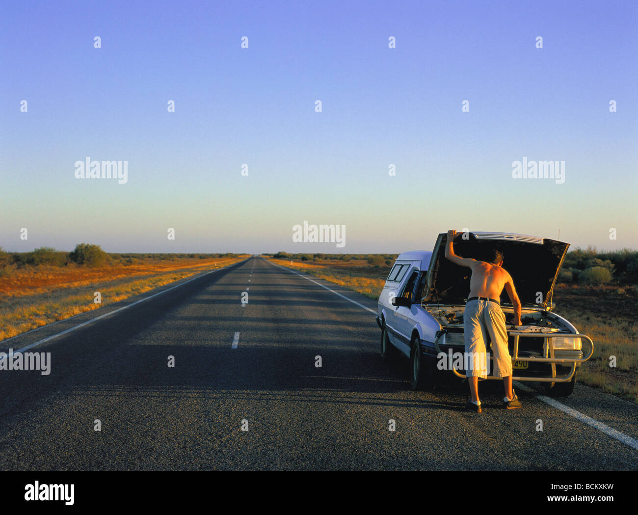 Man looking under hood of car, on side of road Stock Photo - Alamy