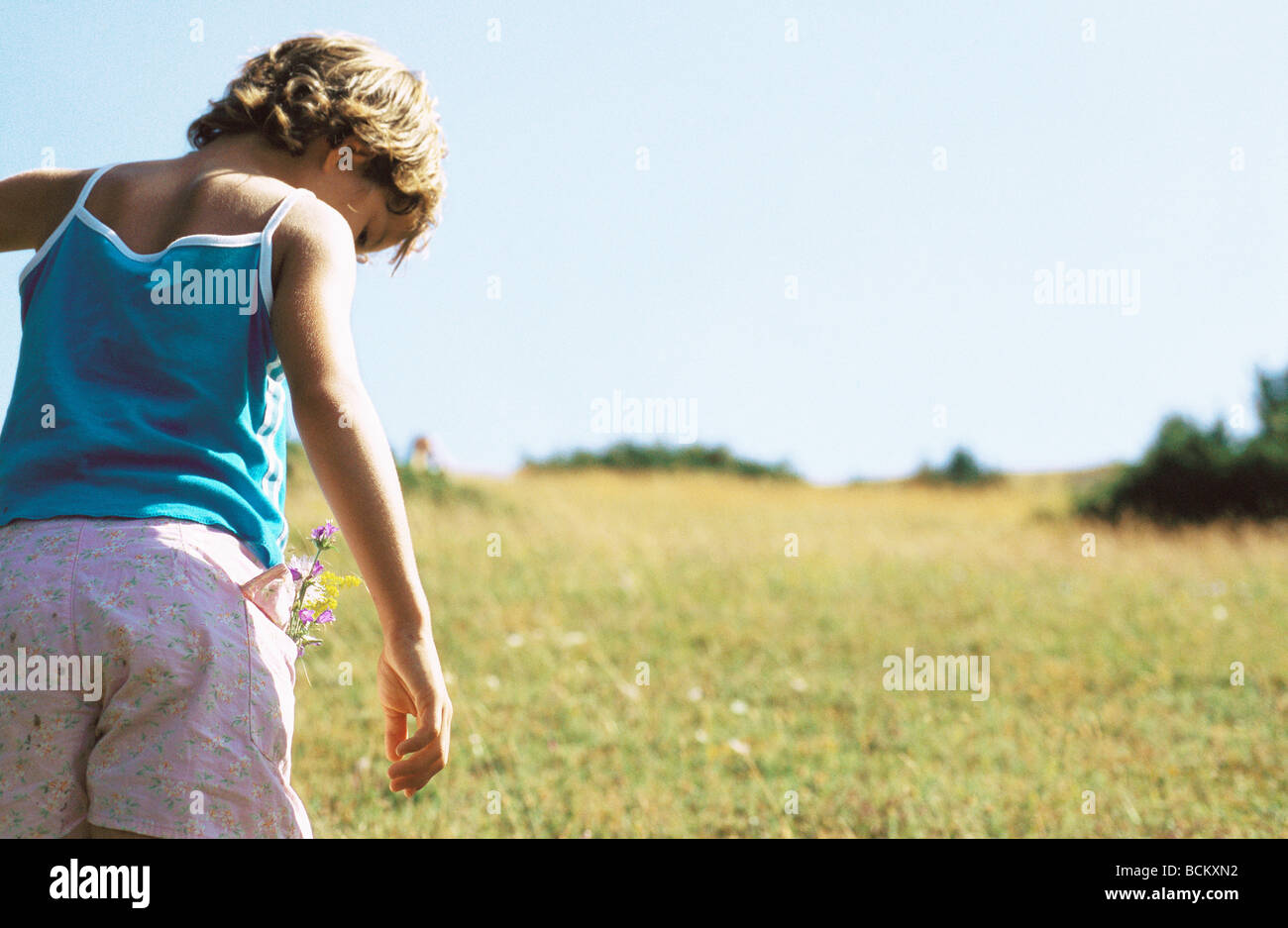Girl standing in meadow, looking down, rear view Stock Photo - Alamy