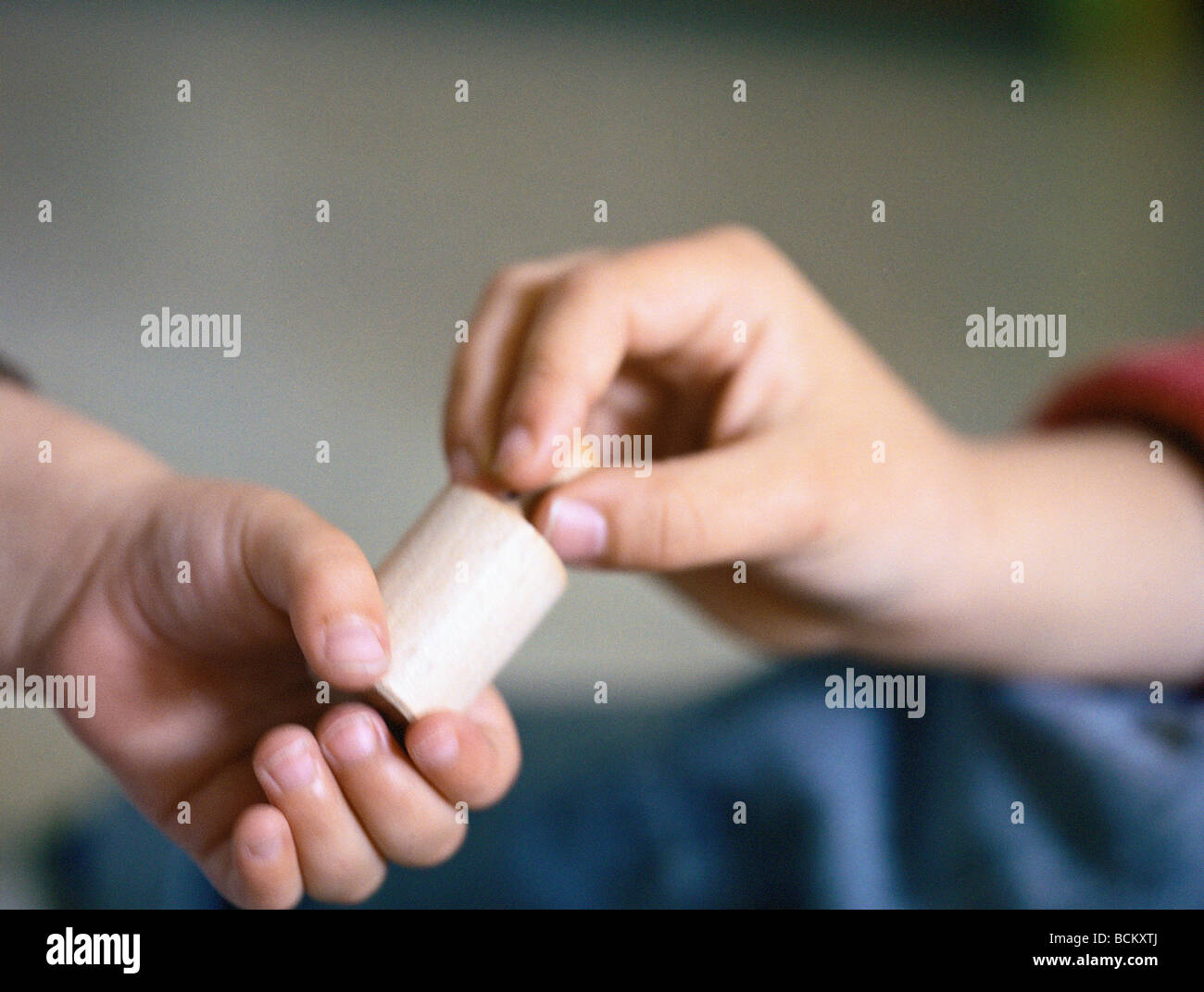 Child handing wooden weight to second child, close-up of hands Stock ...
