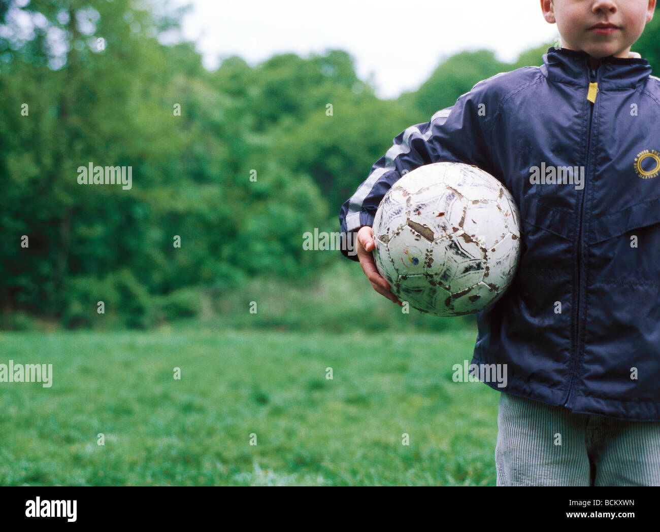 Boy standing with soccer ball under arm Stock Photo - Alamy