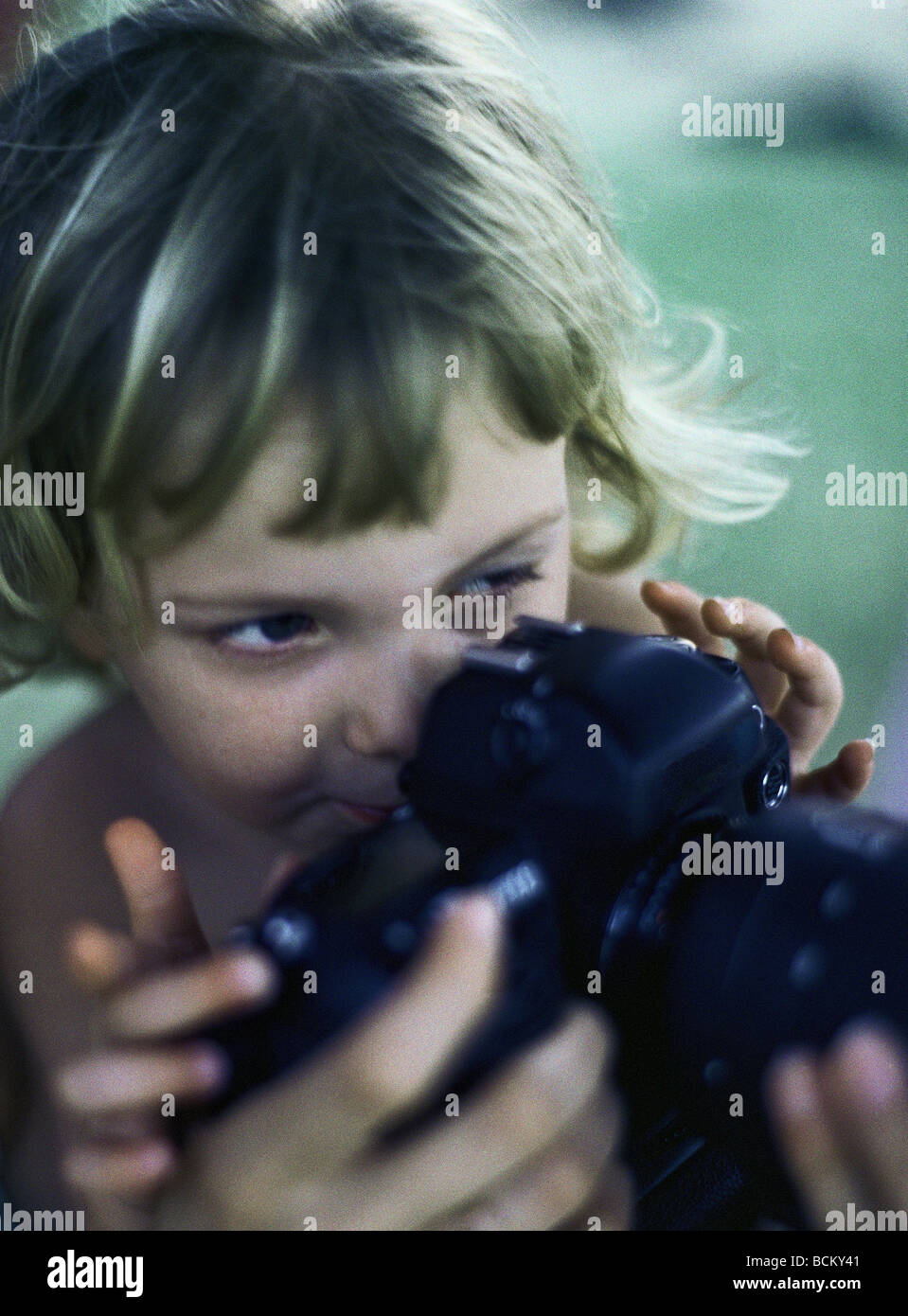 Little girl looking through camera, second person's hands holding ...