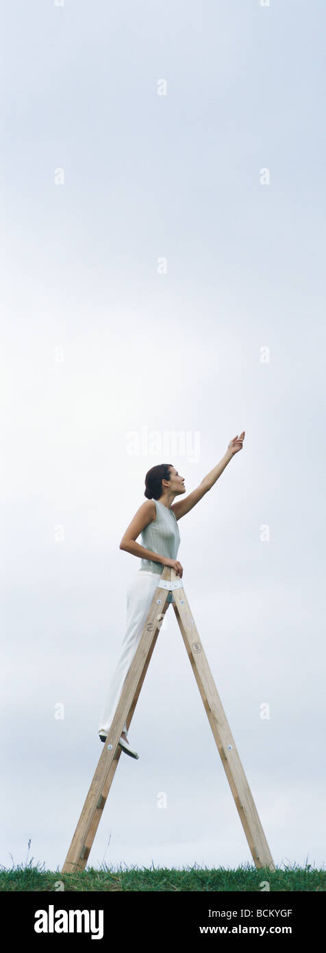 Woman on ladder, reaching toward sky Stock Photo - Alamy