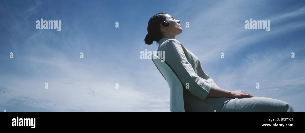 Woman sitting back in chair, sky in background, low angle view Stock ...