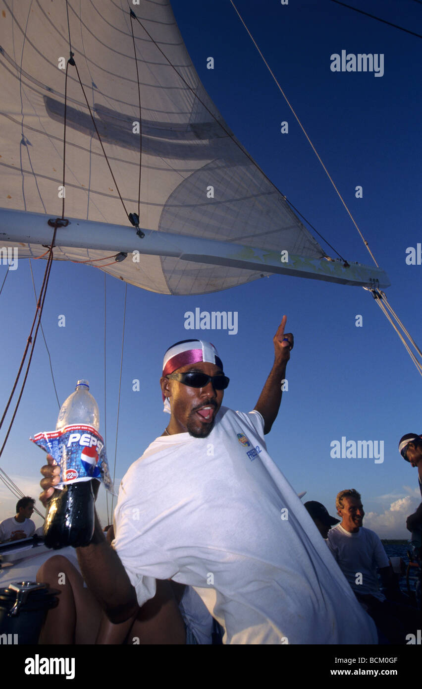 A black man with pirate bandanna dancing at evening on a catamaran ship ...