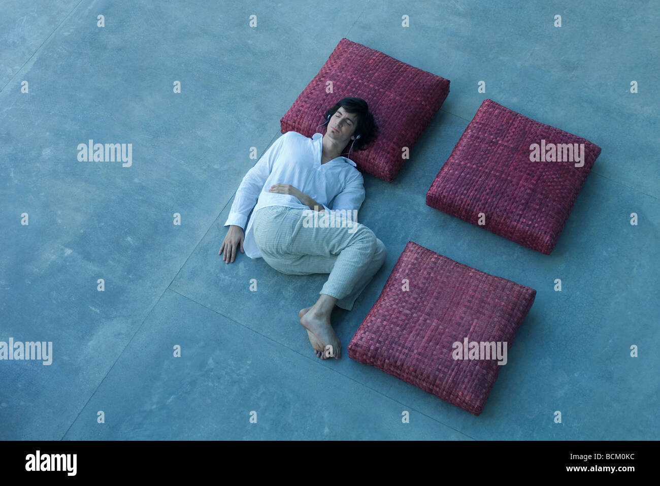 Three square cushions and man arranged in square shape, man lying on ...